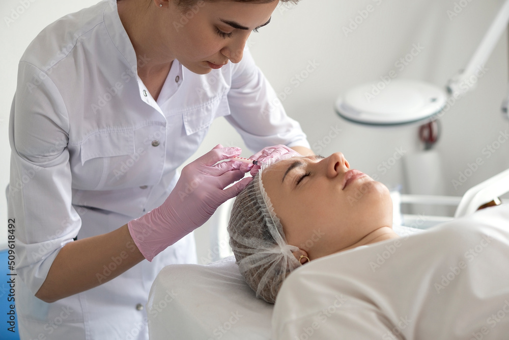 woman doctor cosmetologist dermatologist makes injections of botulinum ...