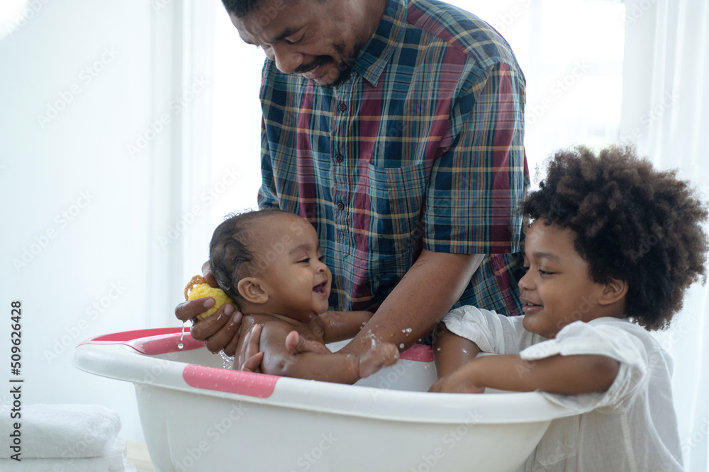 Happy African family, father bathing his baby daughter in bathtub ...