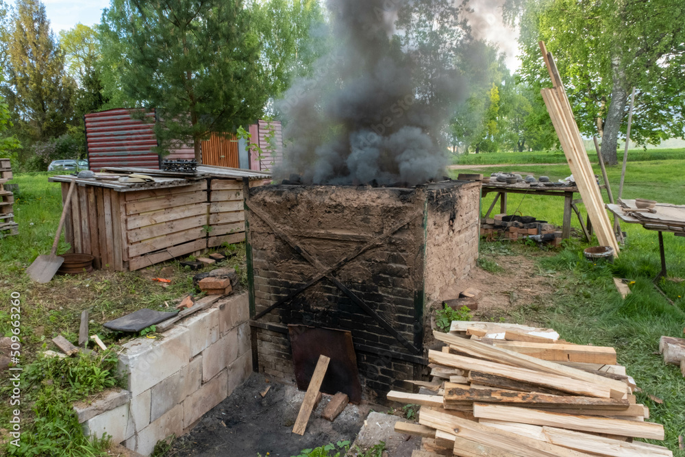 Firing of wood fire kiln is part of process for black pottery. Unique ...