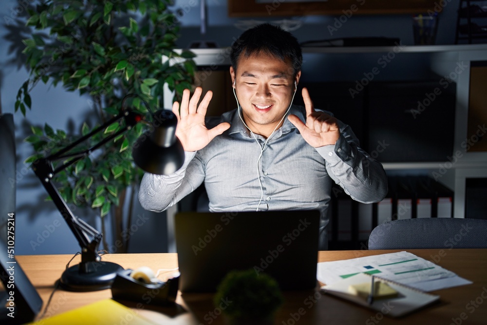 Young chinese man working using computer laptop at night showing and ...