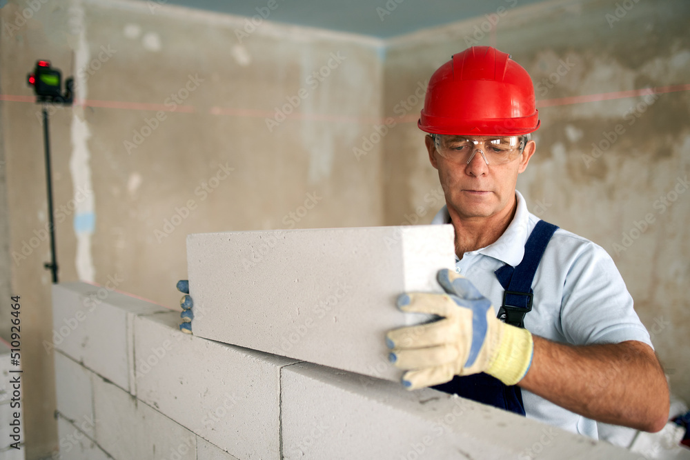 Bricklayer or mason lays bricks to construct wall of autoclaved aerated ...