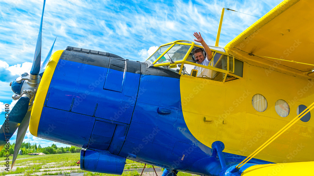 Joyful pilot smiles and waves his hand from the cockpit window of an ...