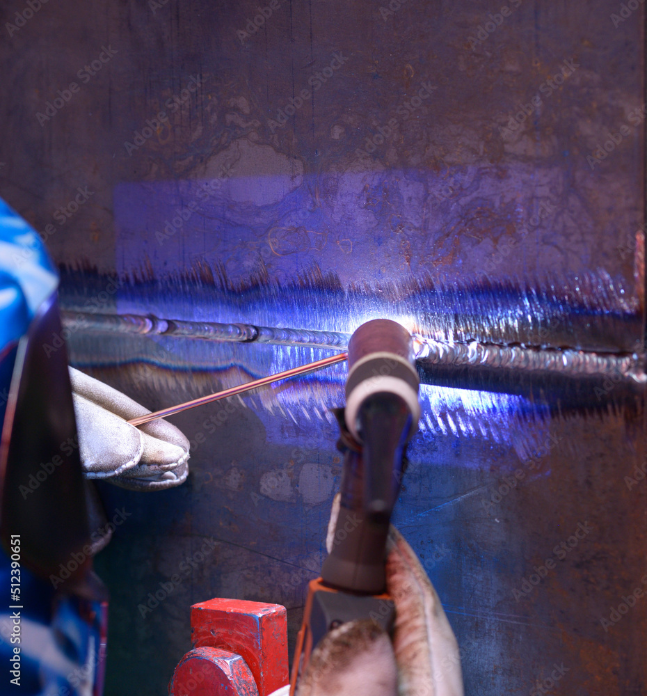 welder hands weld two pieces of metal using argon torch and filler rod ...