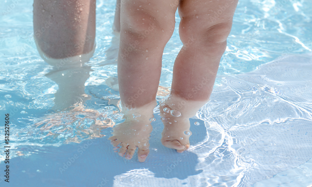 cute little baby legs in pool water or holding feet up,mother is in the ...