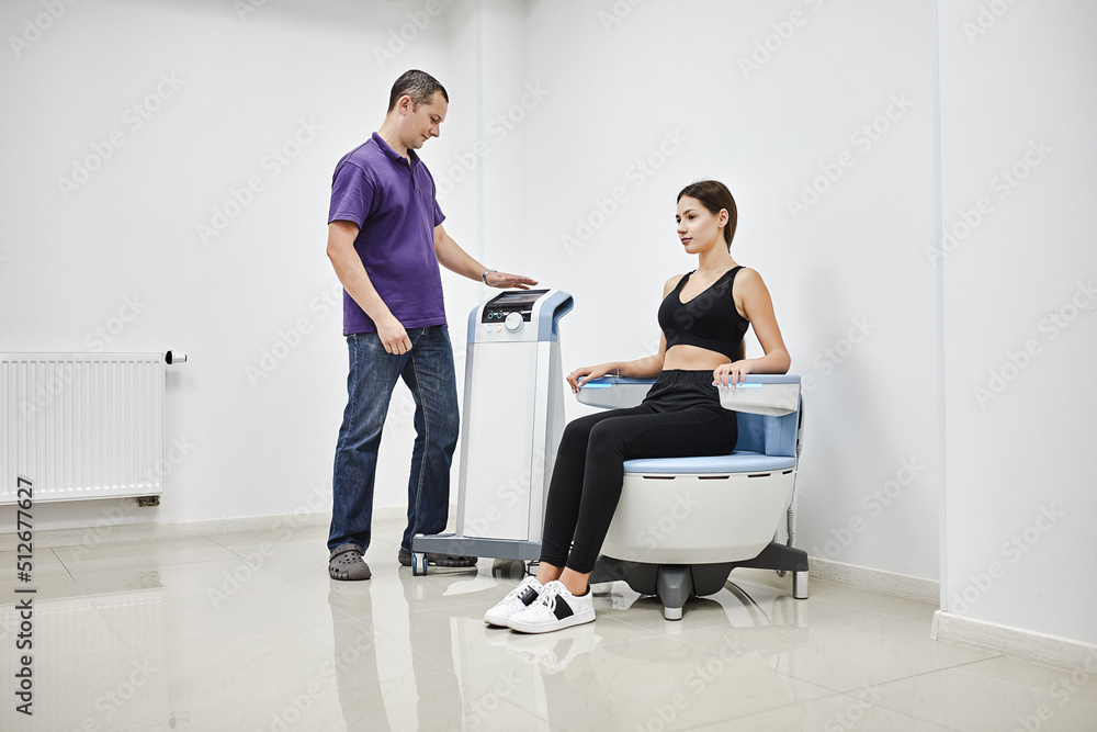 Young woman sitting on electromagnetic chair for stimulation of deep ...