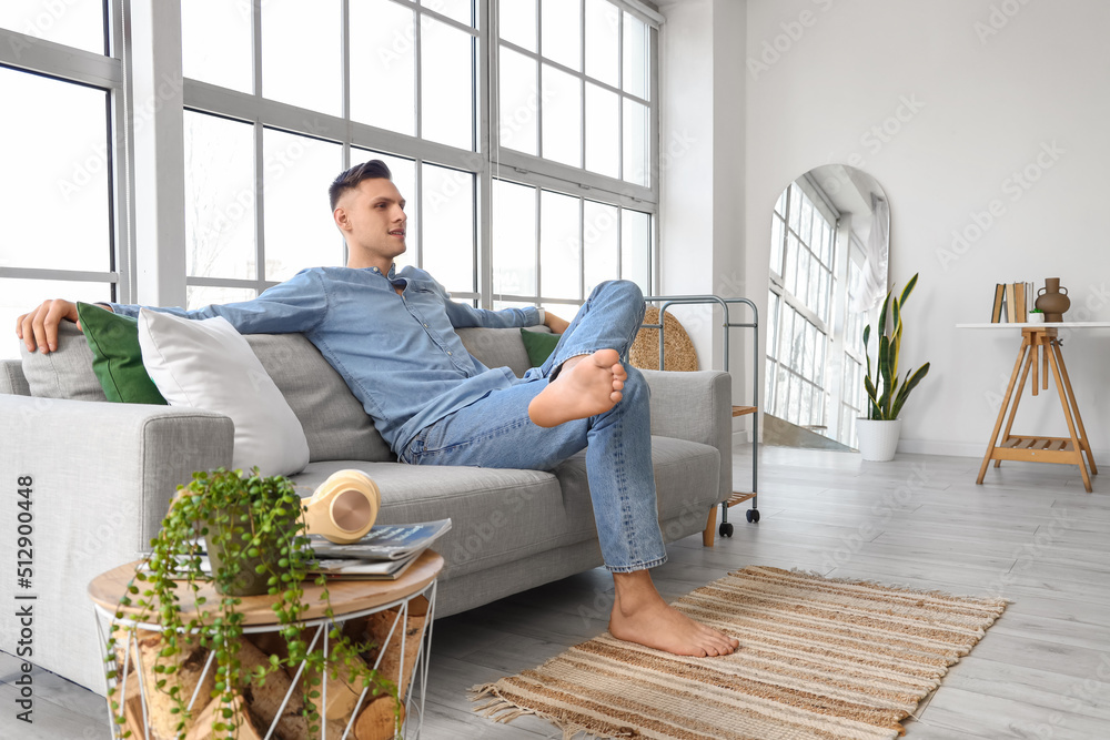 Young barefoot man sitting sofa at home Stock Photo | Adobe Stock