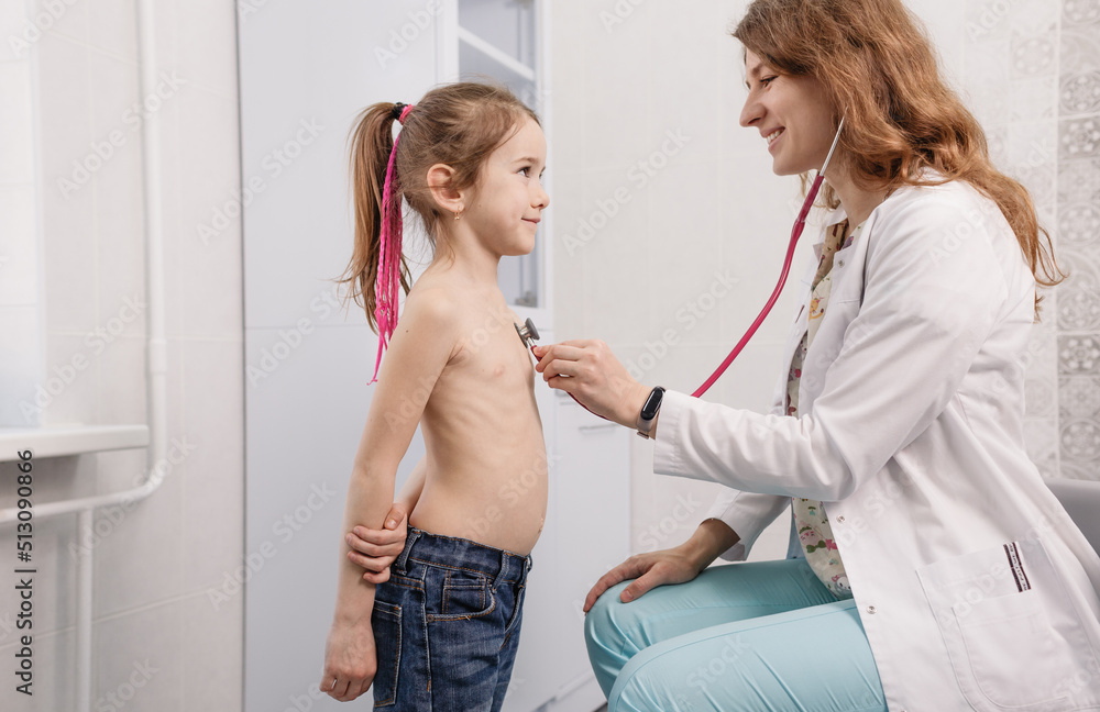 A pediatrician conducts an examination of the child, listens to the heart with a stethoscope ...