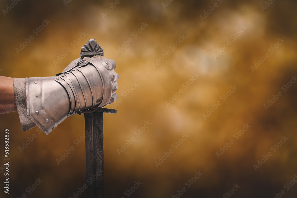 Knight hand with the sword close up on the orange background. Stock ...