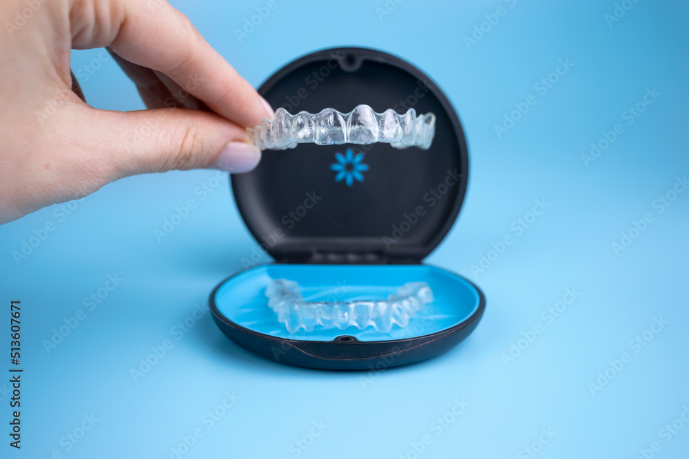 Woman holding invisalign transparent retainers with a box on the table ...