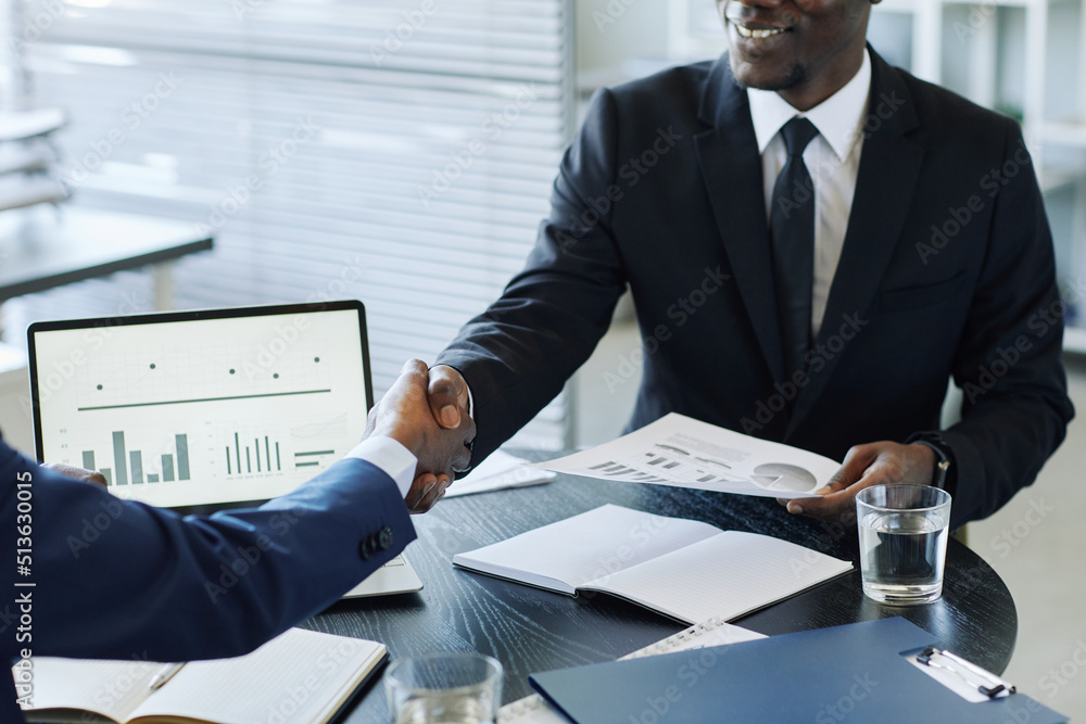 Close up of two impersonal business men shaking hands across meeting ...