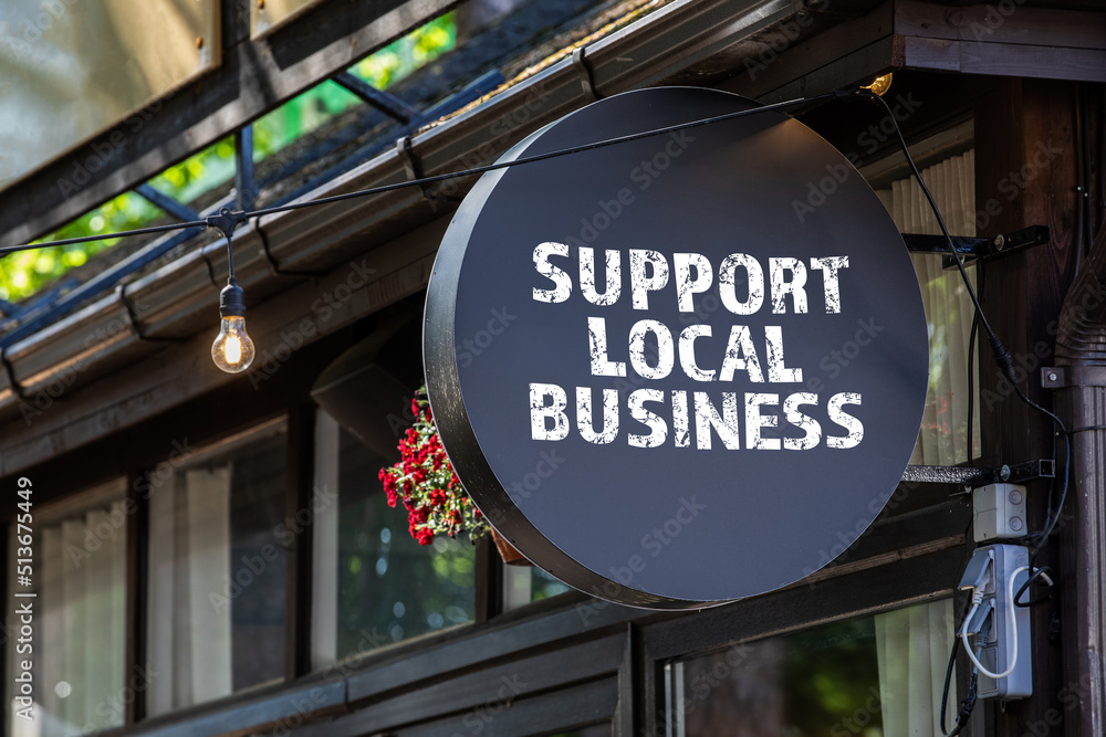 Support local business. Round, black sign onn teh wall of the house ...