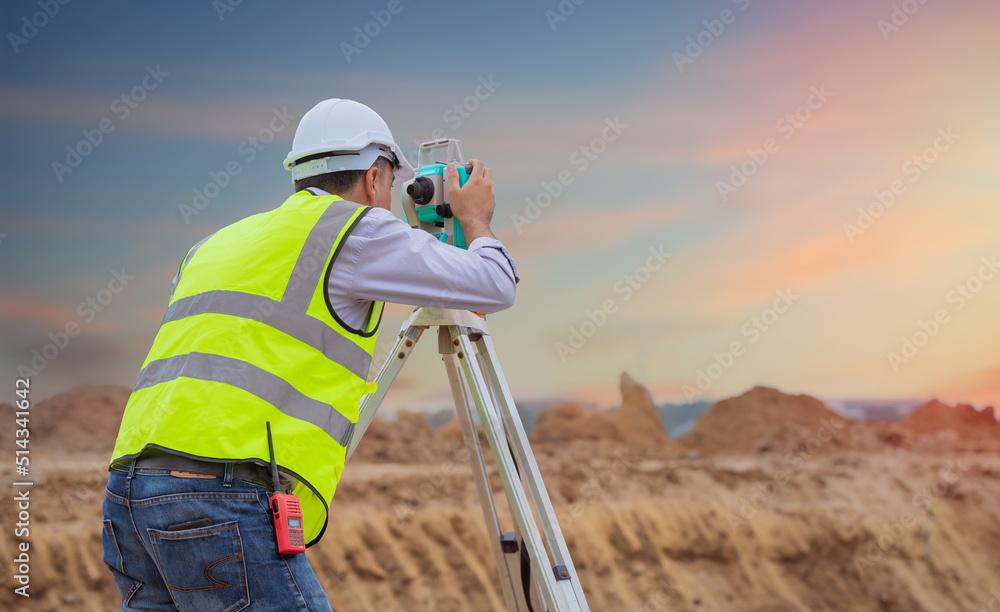 Surveyor engineer wearing safety uniform and helmet with equipment ...