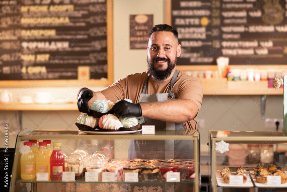 male coffee shop owner near showcase with cakes and desserts in his ...