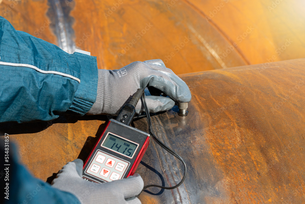 Inspector is measuring thickness of the pipe material from near to weld ...