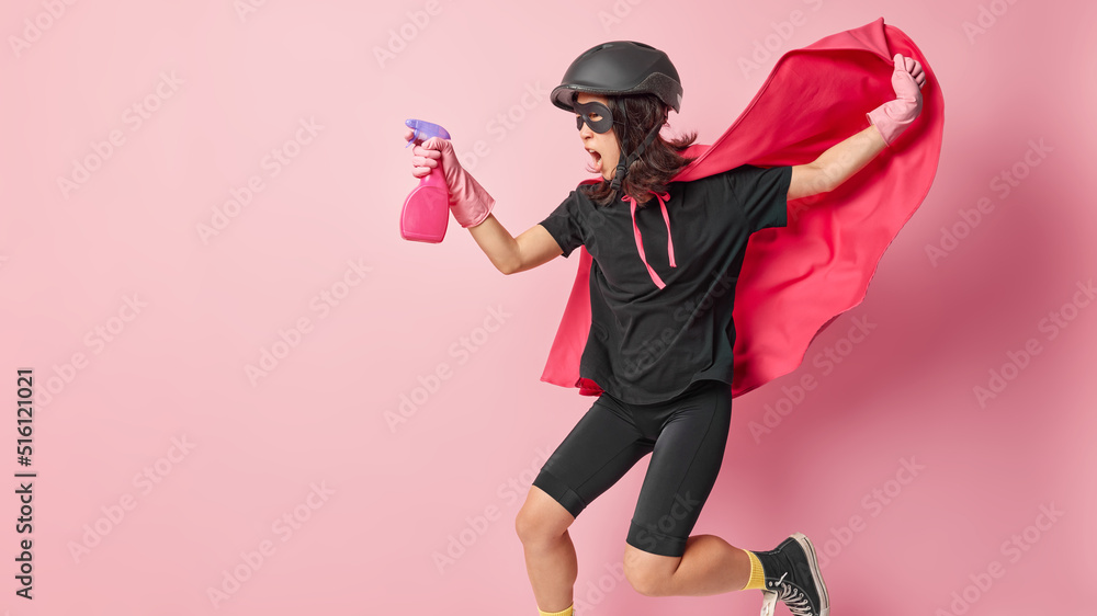 Horizontal shot of emotional young woman jumps in air sprays detergent ...