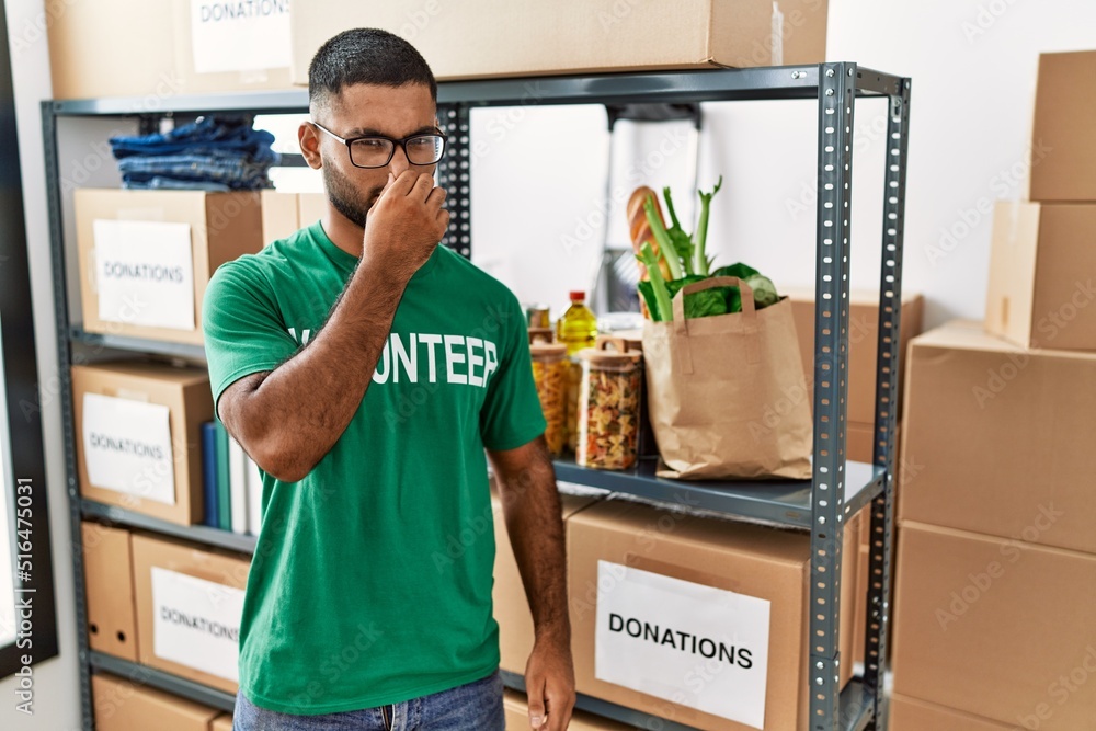 Foto de Stock Young indian man volunteer holding donations box smelling ...