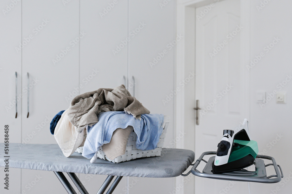 Neat stack of clean freshly laundered clothes and electric iron on ...