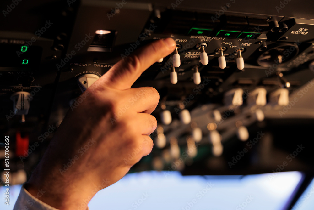 Aviation pilot using control panel in cockpit to fly airborne aircraft ...