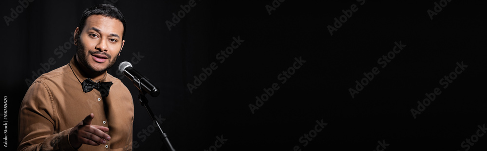 indian comedian telling jokes into microphone and pointing with finger ...