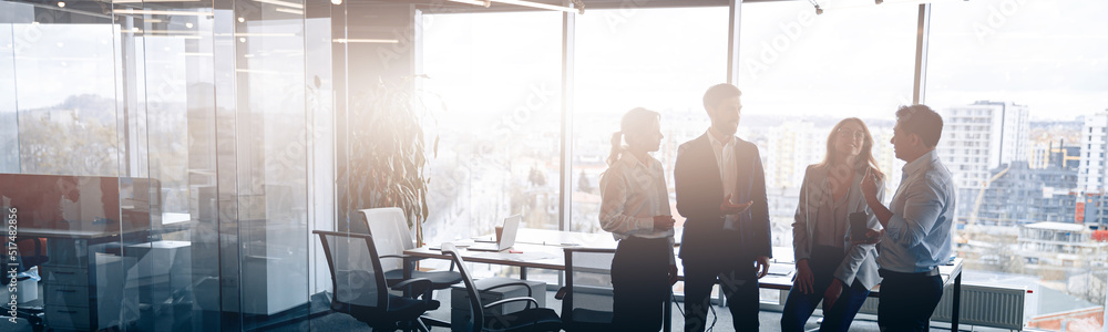 Business team standing against panoramic windows in modern office ...