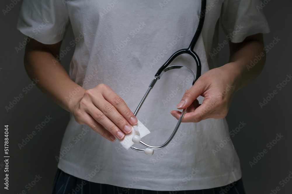 Lady hand applying alcohol wipe hand sanitiser towards the Stethoscope ...