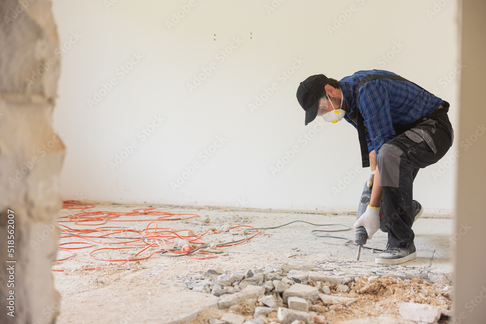 View of a construction worker using a hand-held demolition hammer and ...