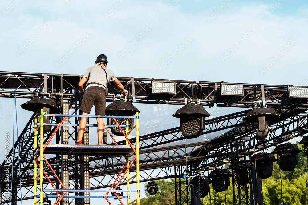 Installation of lighting equipment on a mobile concert stage. A worker ...