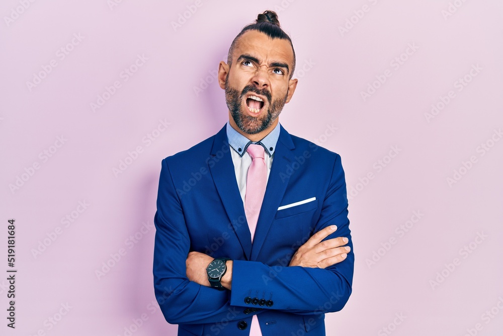 Young hispanic man wearing business suit with arms crossed gesture ...