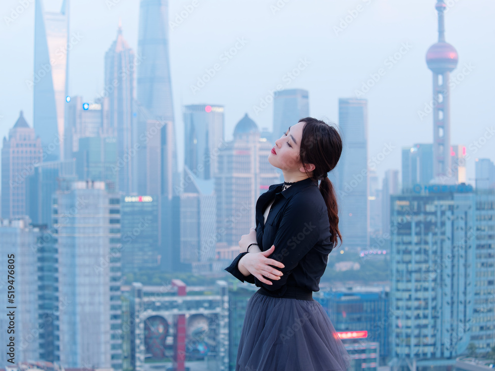 Beautiful young Chinese woman in black arms crossed on top of mansion ...