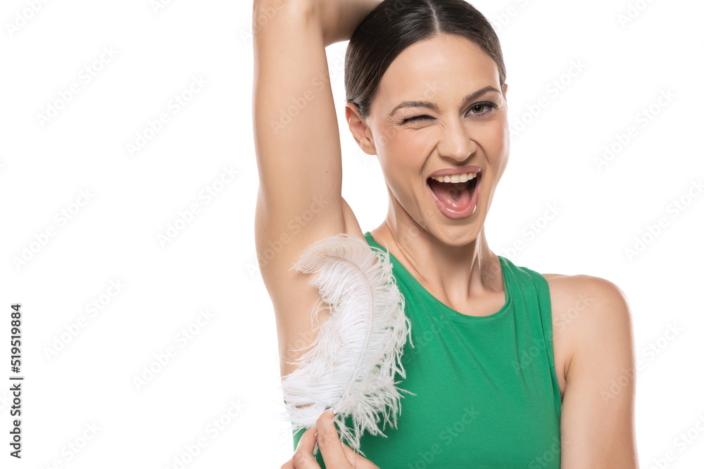 Beautiful happy woman lifting hand up, touching her armpit with feather ...