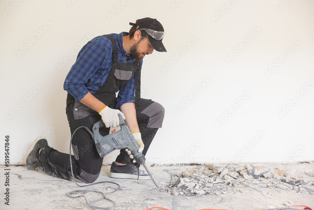 View of a construction worker using a hand-held demolition hammer and ...