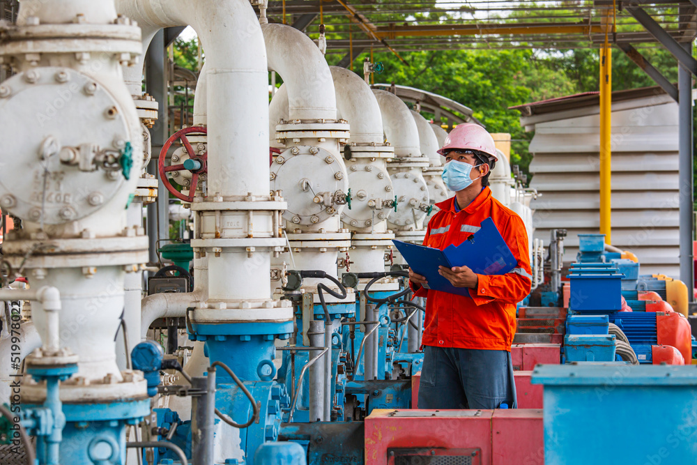 Male worker inspection pump motor oil at steel long pipes and pipe ...