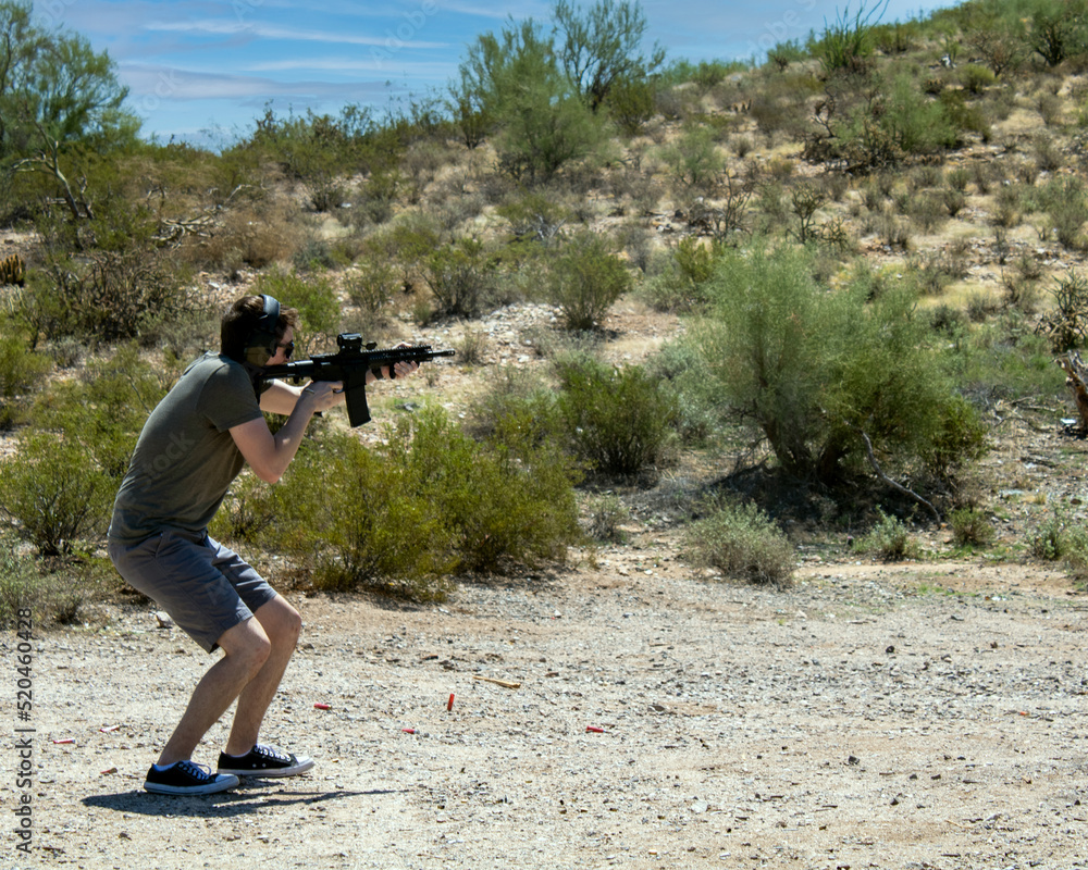 Male holding gun firing at targets on shooting range with a custom ar15 ...