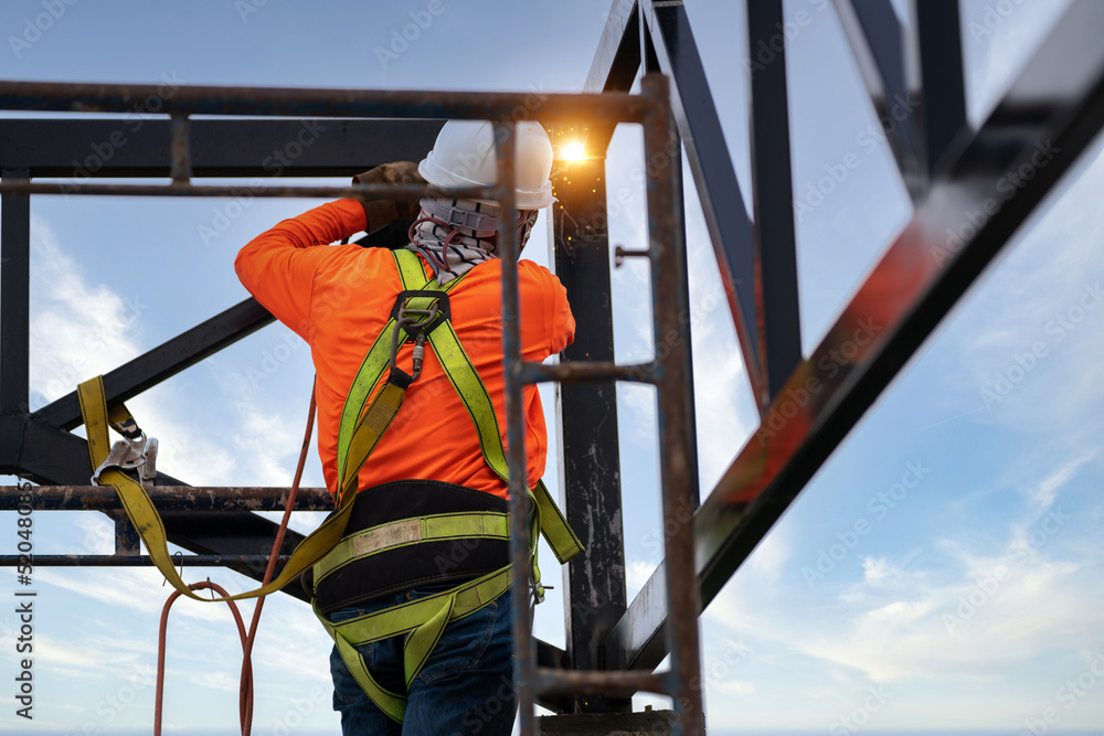 Industrial steel roof truss welders wear safety clothing on the ...