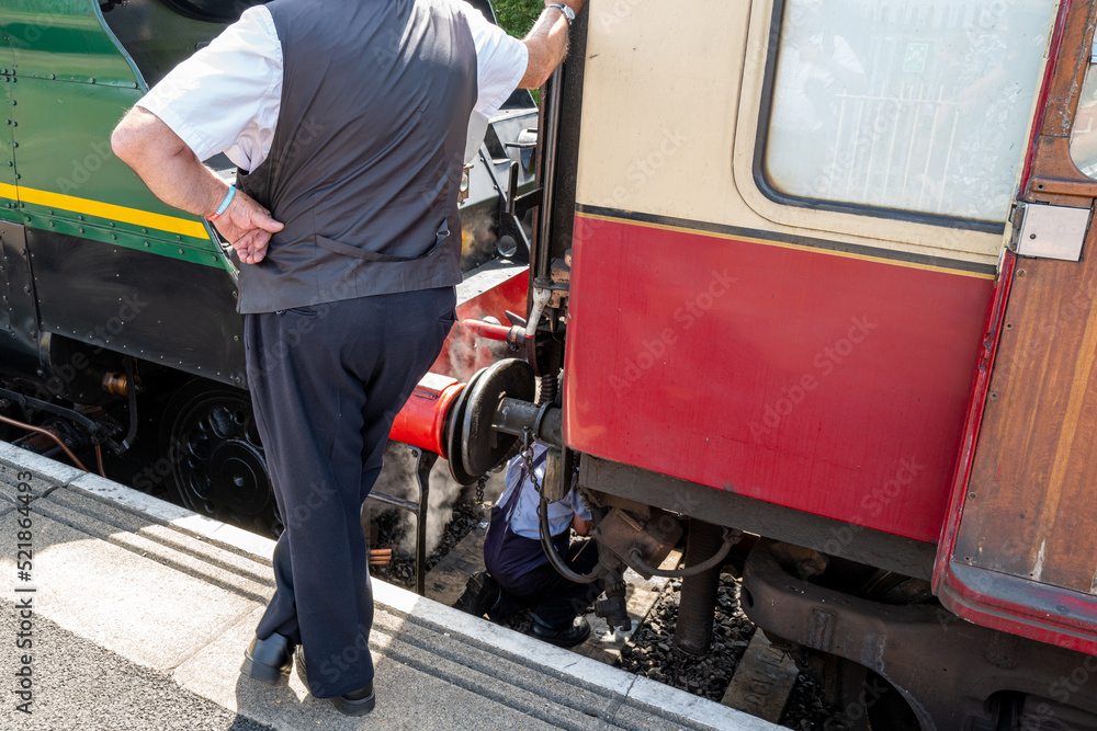 Station manager seen on a railway platform while a steam train driver ...