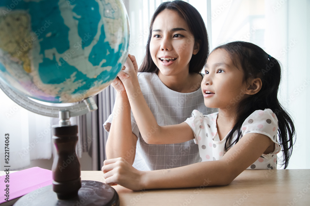 Asian two-generation family learning with a ball pattern of the earth. Ecology concept ...