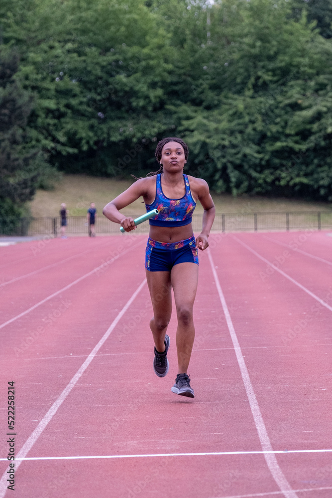 Female runner with baton on running track Stock Photo | Adobe Stock