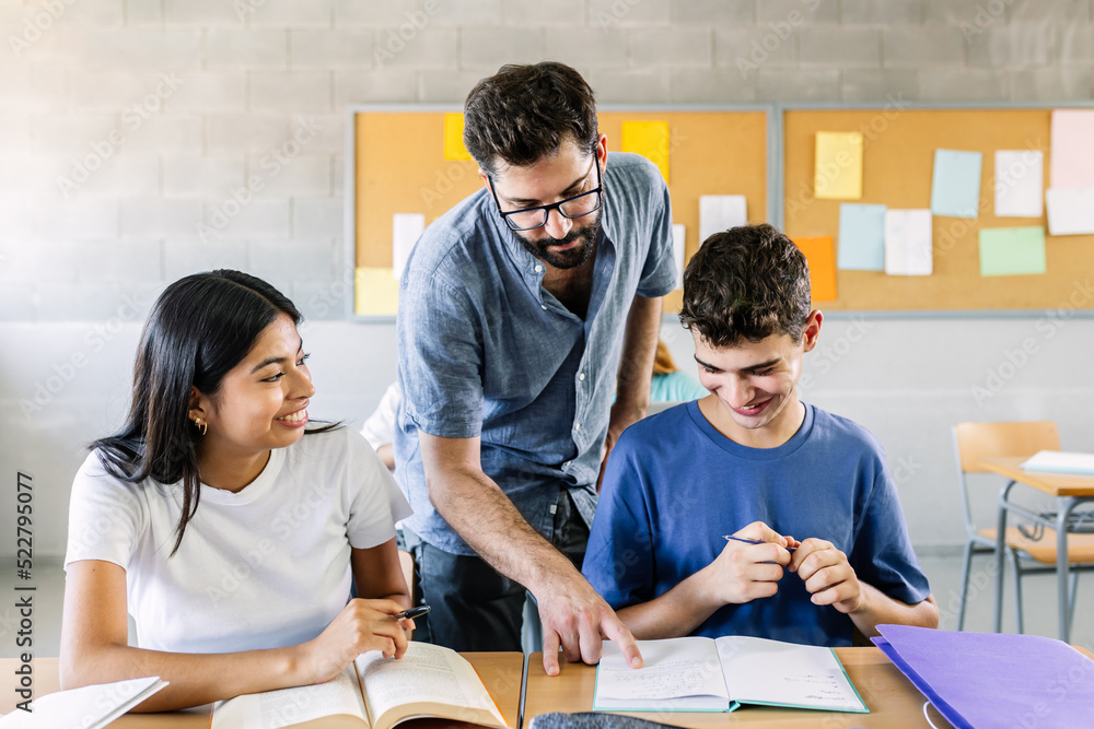 Foto de Stock Male teacher helping high school students doing exercises in classroom - Education ...