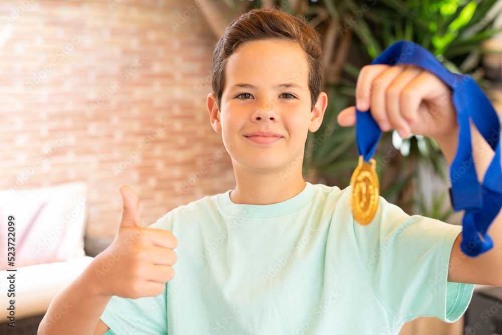 Cute child boy showing his gold medal with thumb up standing on the ...