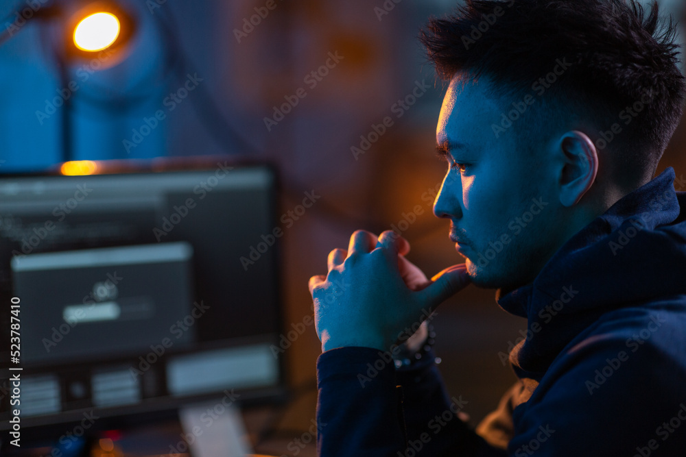 cybercrime, hacking and technology concept - close up of male hacker in dark room using computer ...