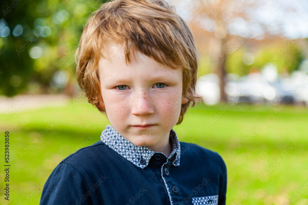 Horizontal portrait of unsure little boy with autism, at park outside ...