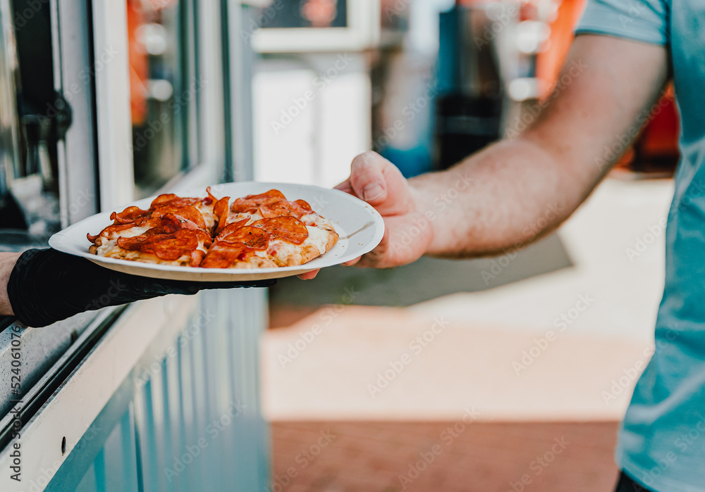 chef hands gives a pita mini pizza to man from food truck on street ...