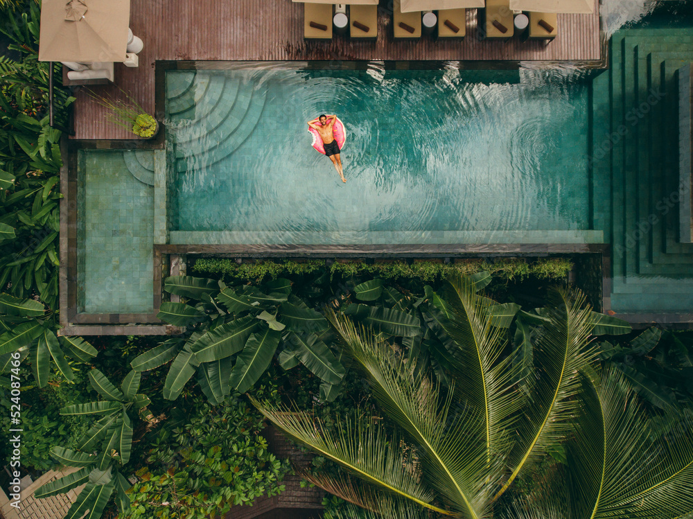 Young man relaxing in resort swimming pool Stock Photo | Adobe Stock