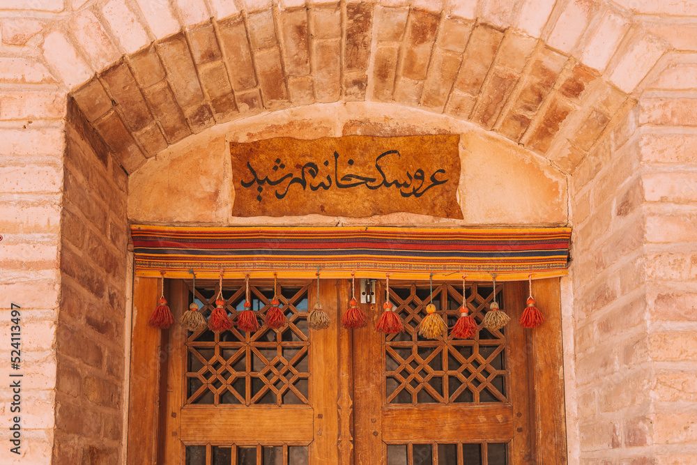 Entrance of old Iranian building with wooden door and Arabic script ...