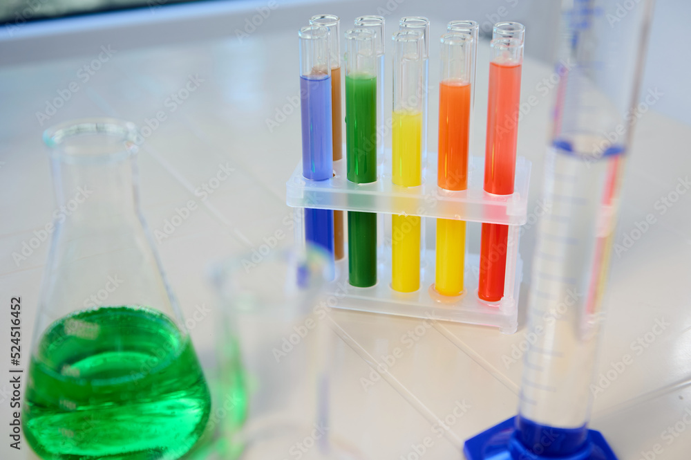 Close-up test tubes with colorful chemical liquids on tripod and a ...