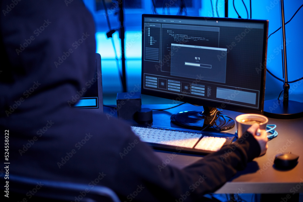 cybercrime, hacking and technology concept - close up of hacker in dark room drinking coffee and ...