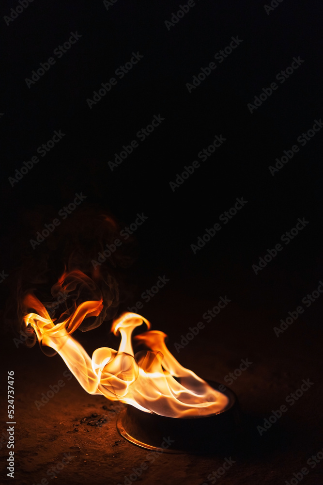 orange fire on a dark background. Burning kerosene in an iron plate. a ...