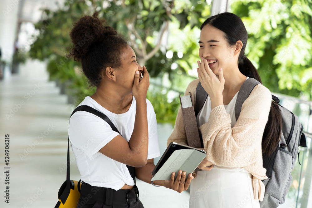 Asian and African college student talking and laughing together, happy ...