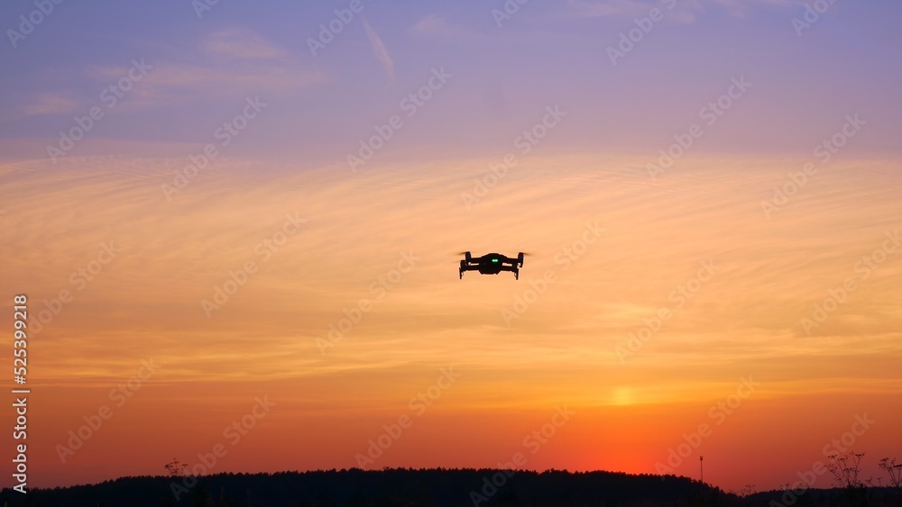 The drone moves from side to side in the bright sunset sky. The ...