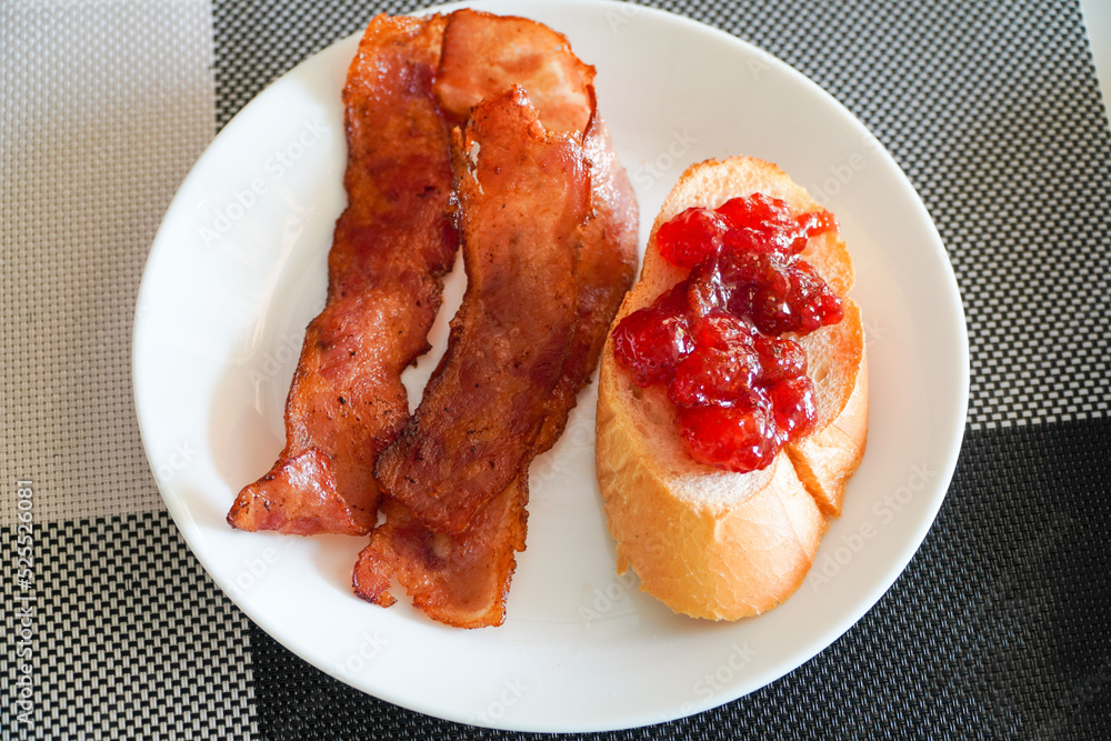 Bread topped with strawberry jam and bacon Light breakfast in the hotel ...